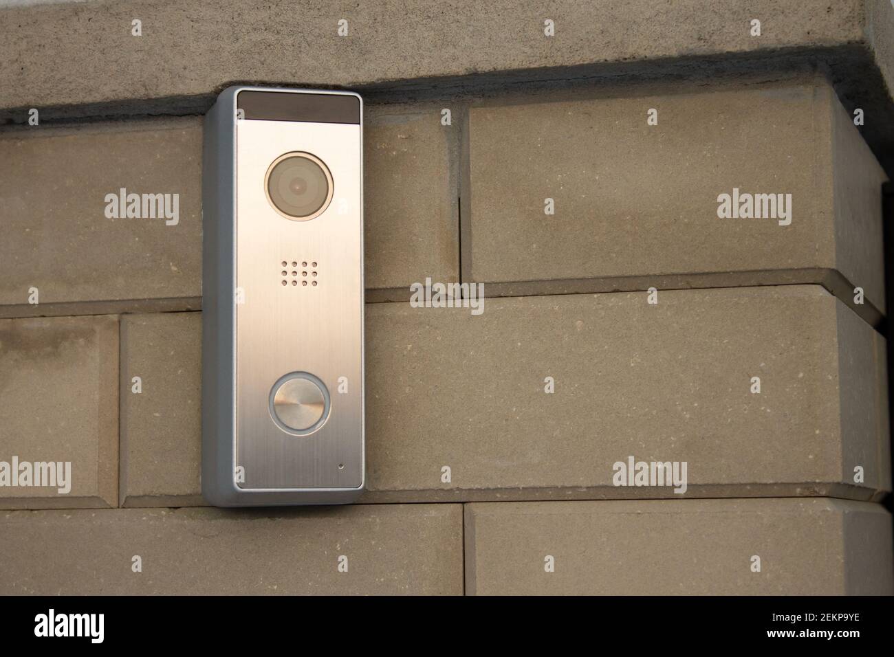 Silver intercom panel with video camera on a brick beige fence pillar ...