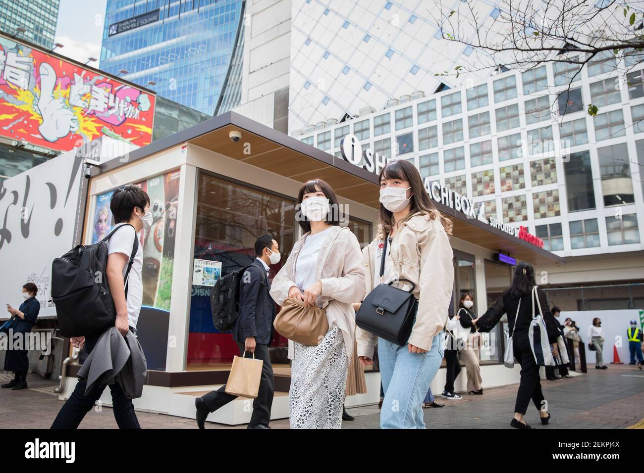 People wearing face masks walk past a newly opened tourist information ...