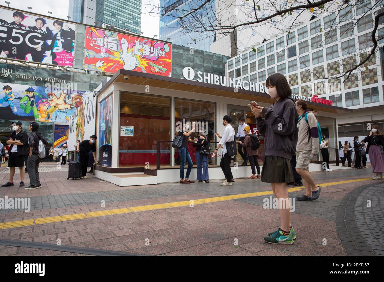 People wearing face masks stand in front of Shibuya’s new tourist information centre ‘Shibu ...