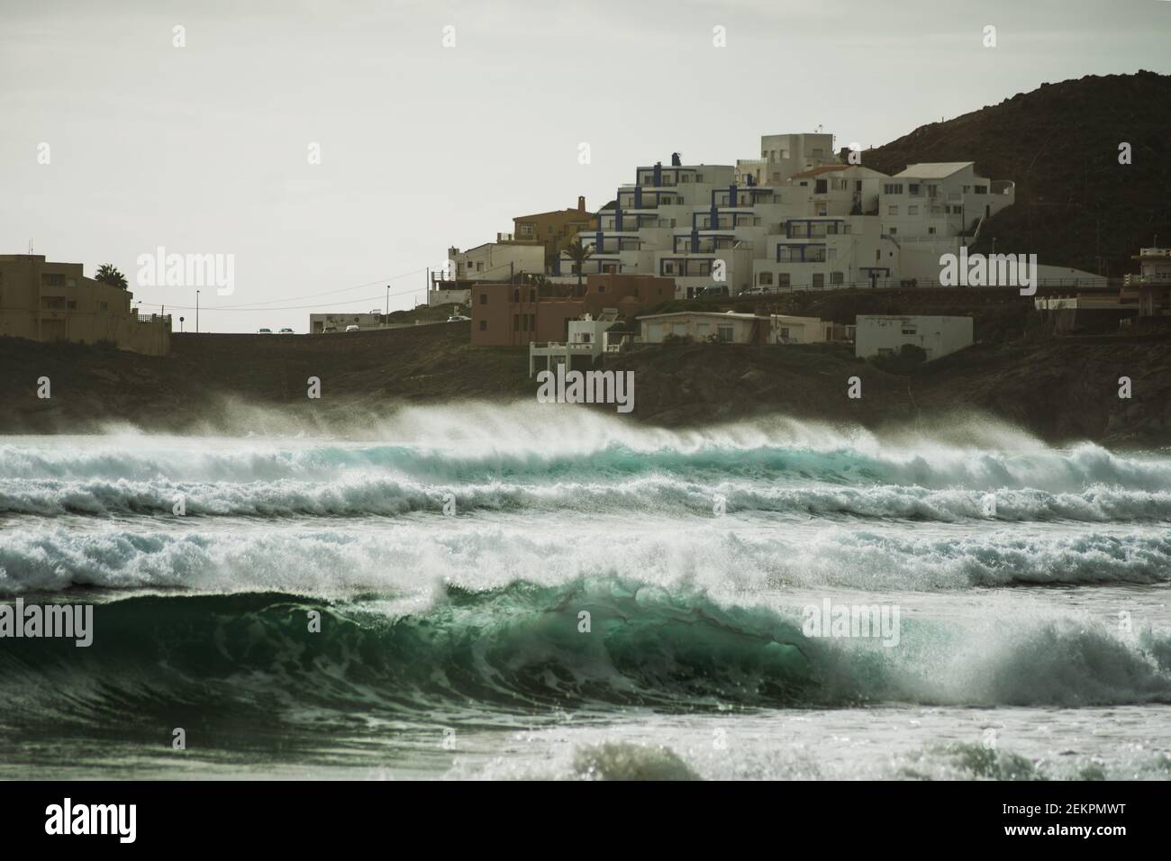Wave breaking on the beach with houses in the background, surf, surfer ...