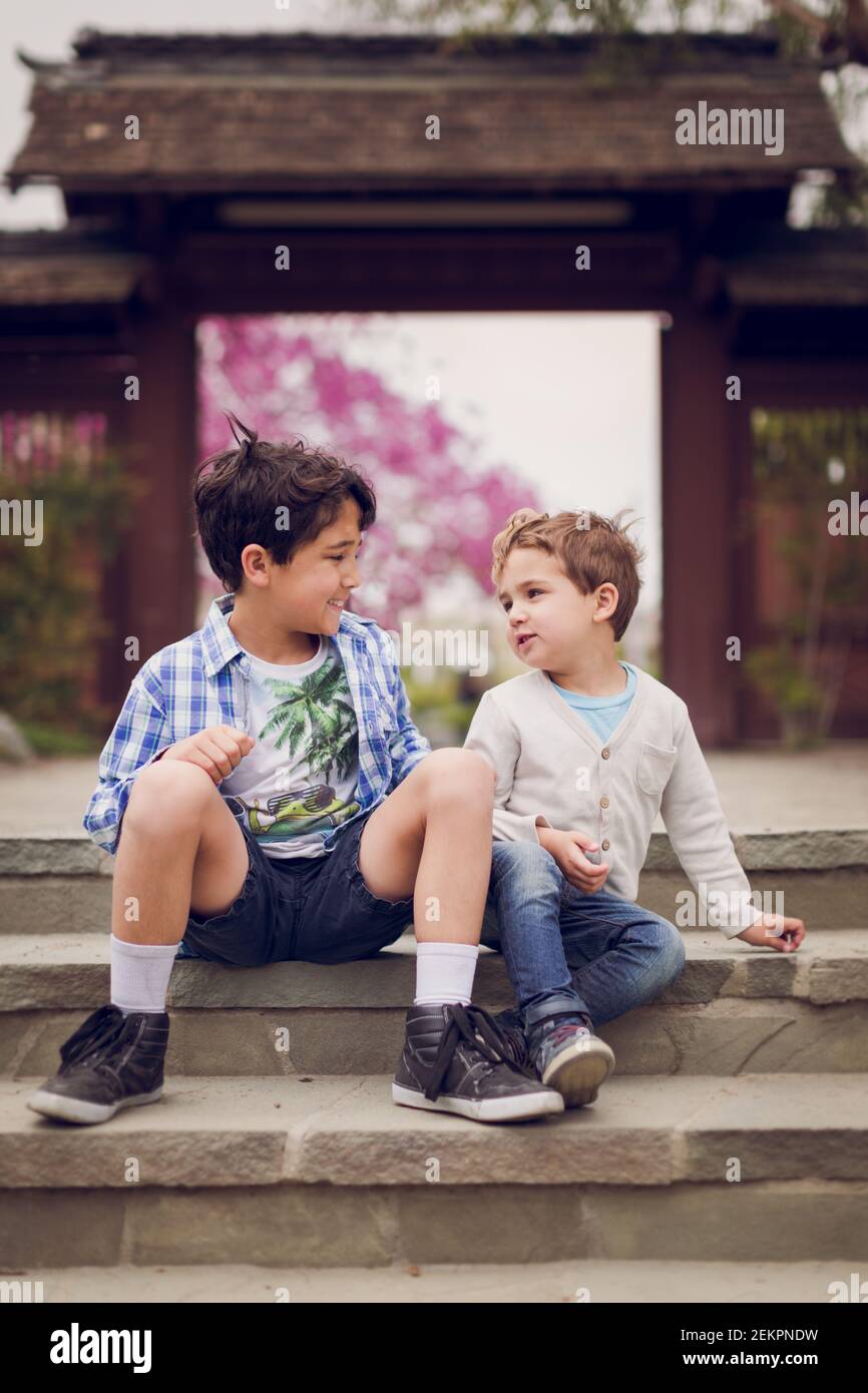 Two brothers sitting on the steps talking to each other Stock Photo - Alamy