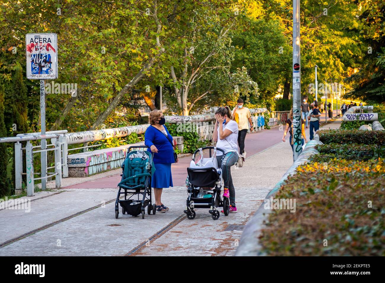Women wearing face masks walk with baby carriages on the street. The ...