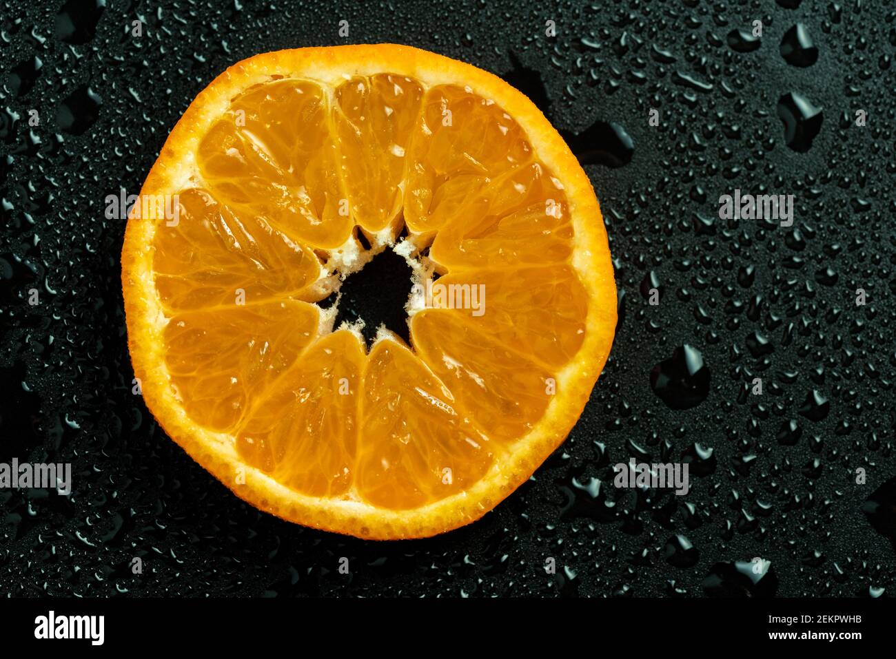 Mandarin slice, detailed closup against black background coverd with ...