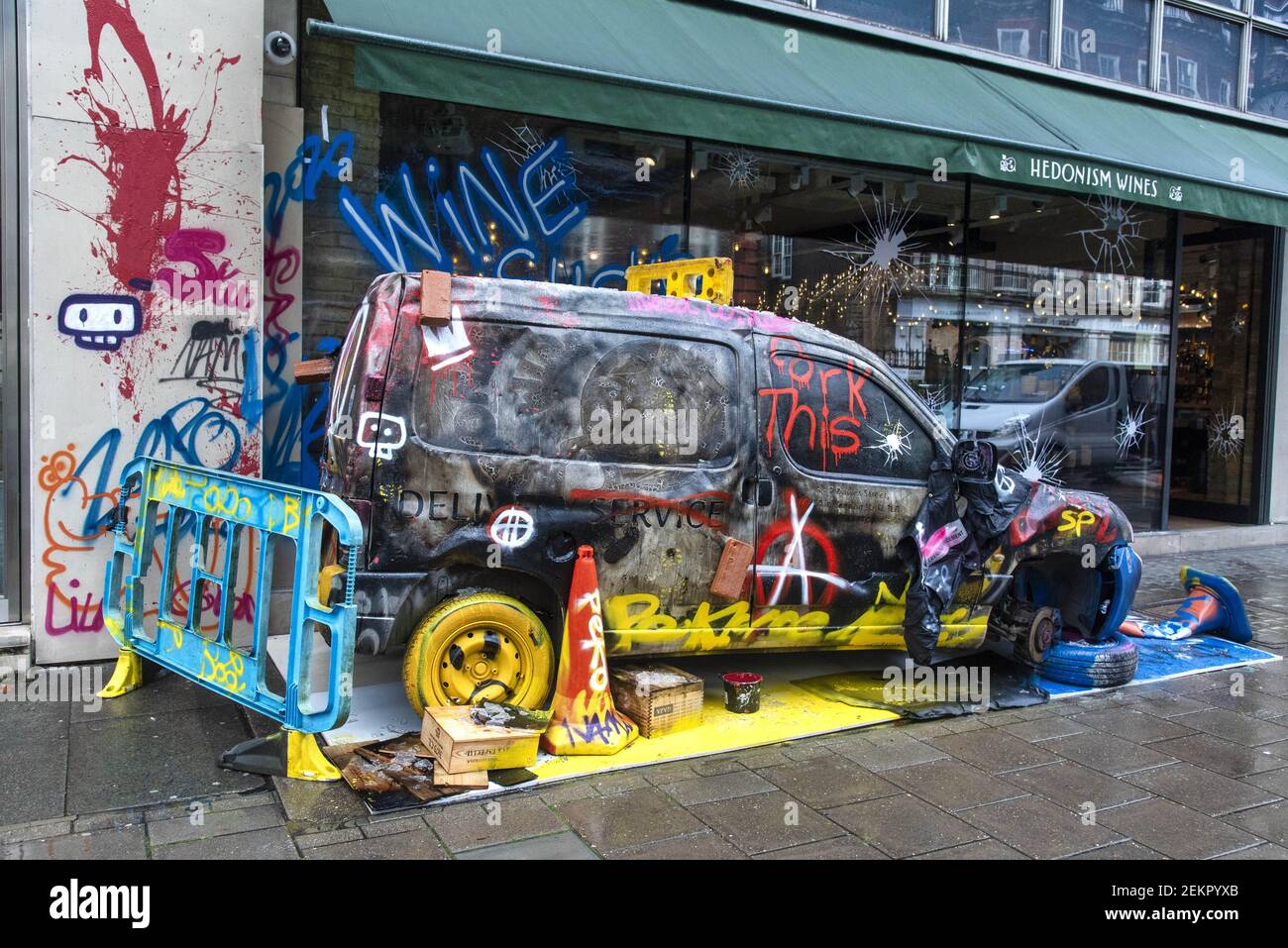 An art installation of a wrecked car with graffiti on it by Hedonism ...