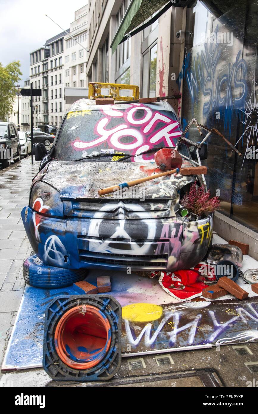 An art installation of a wrecked car with graffiti on it by Hedonism ...