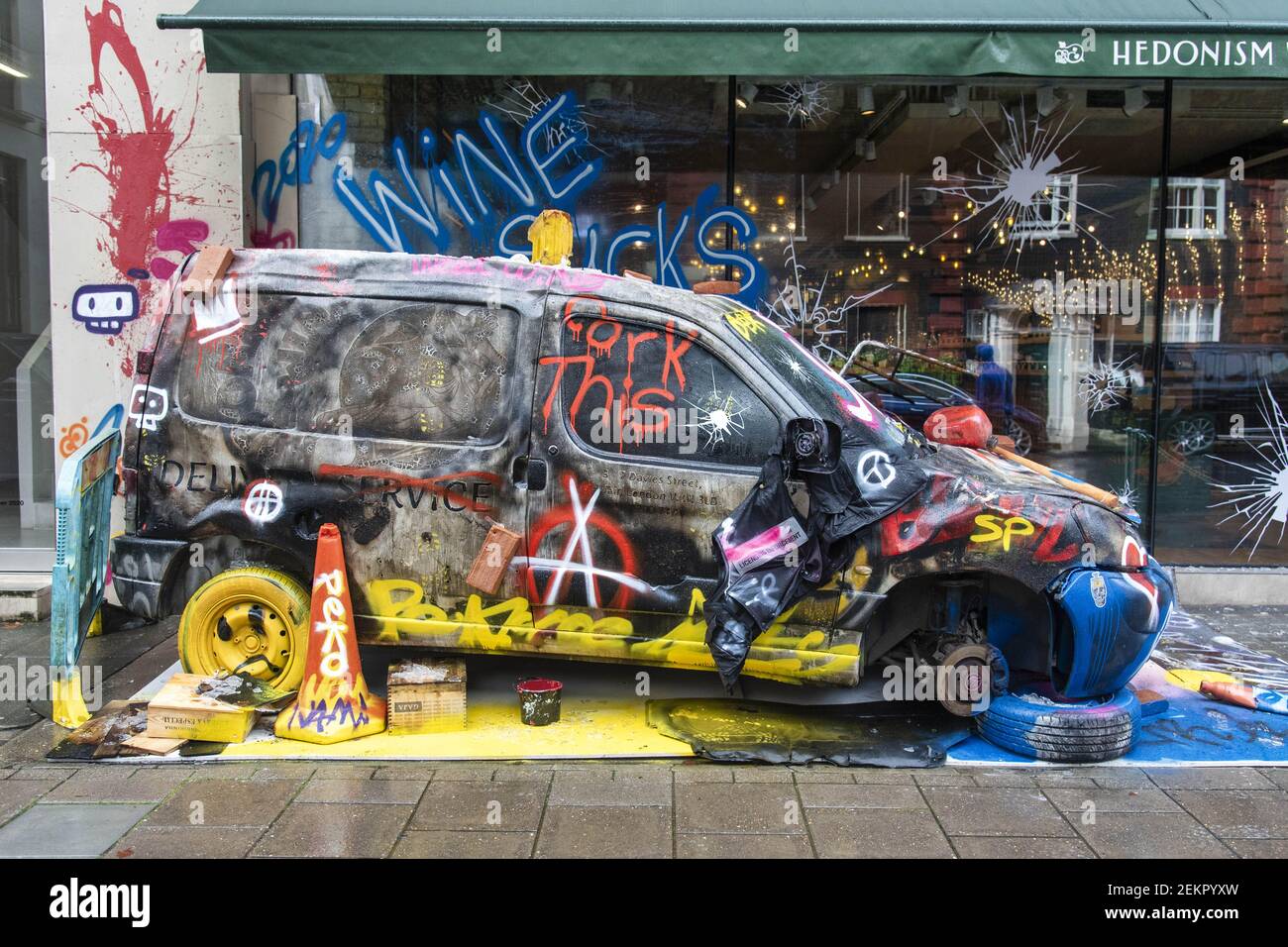 An art installation of a wrecked car with graffiti on it by Hedonism ...
