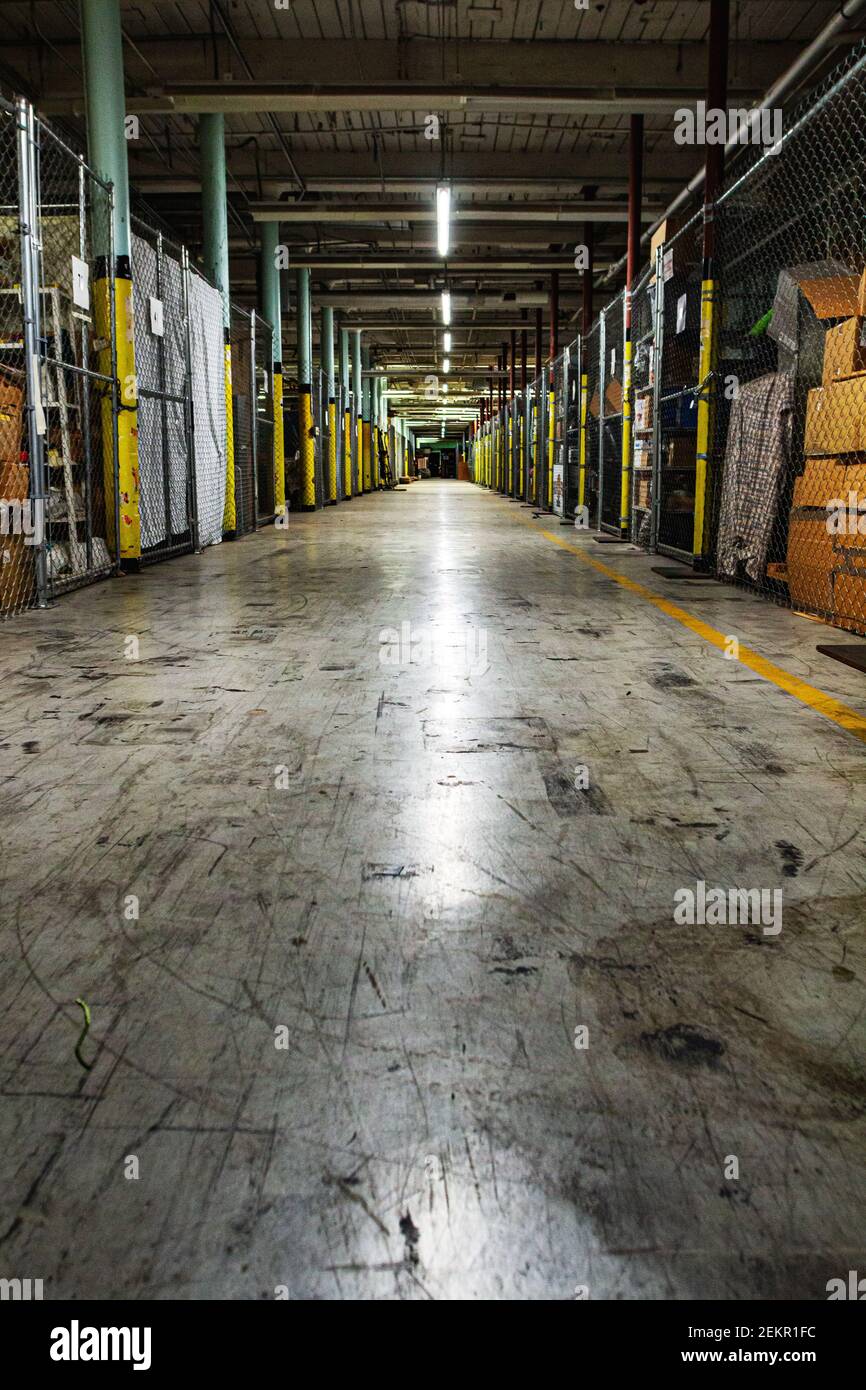A grungy hall in a factory converted to storage units creates leading ...