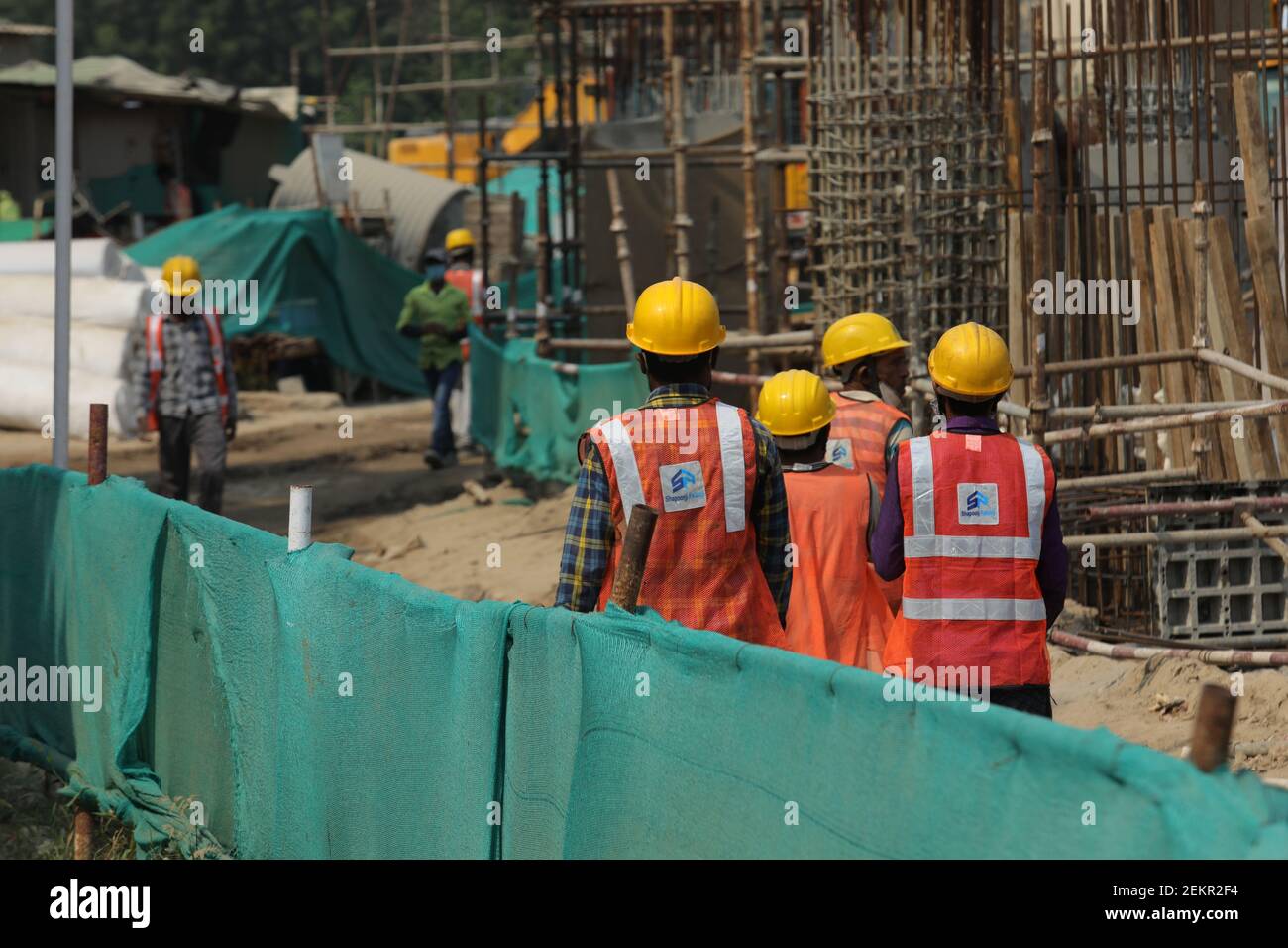 Workers wearing reflective jackets and helmets at a construction site ...