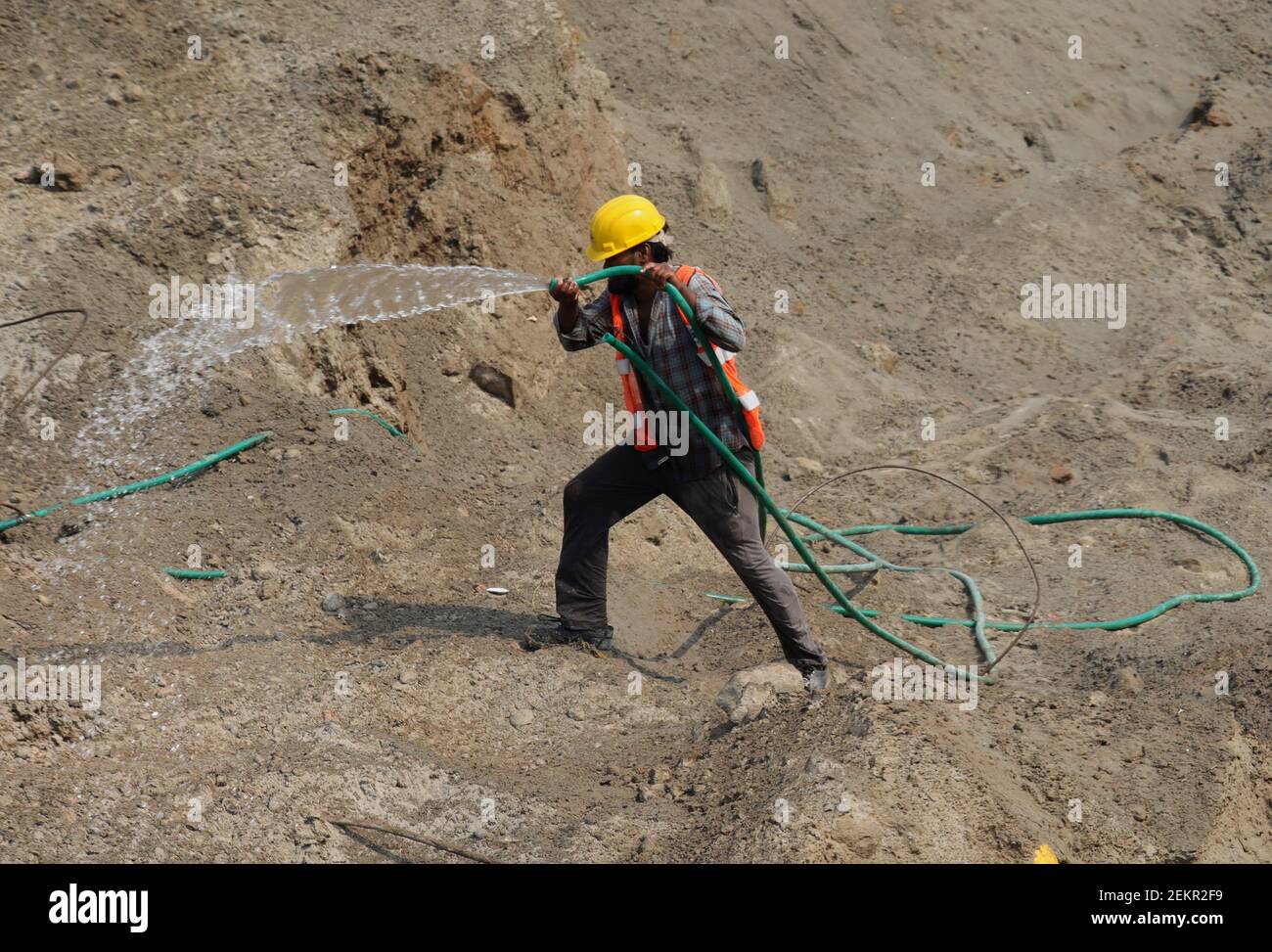 A worker spraying water at the construction site of Integrated ...