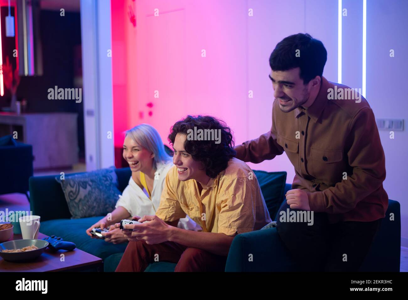 Happy young people playing video games on console while sitting on ...
