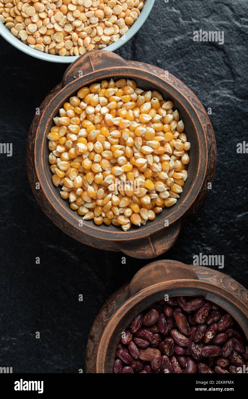 Different kinds of bean seeds, lentil, peas in dishes on a dark ...