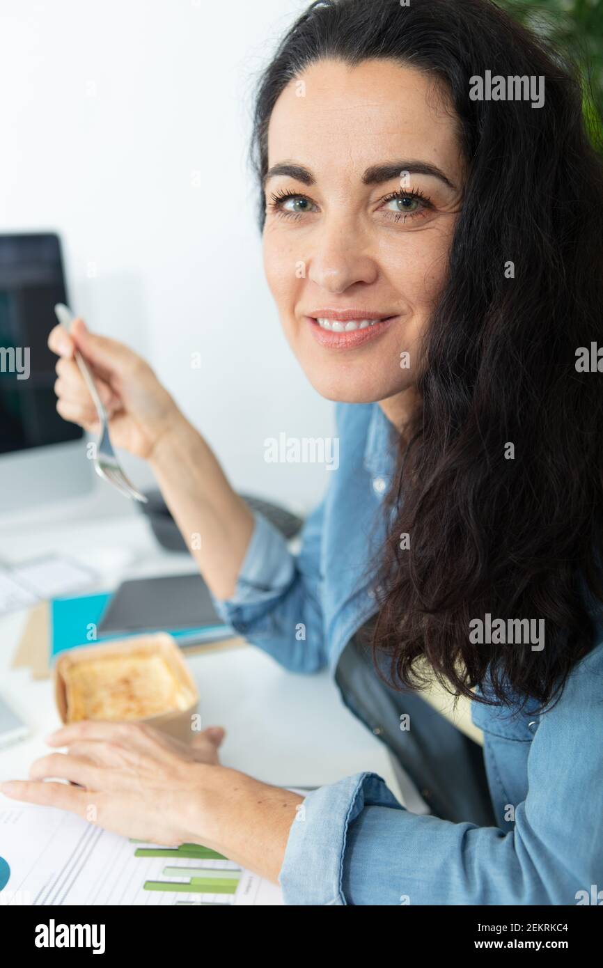 businesswoman eating at office desk Stock Photo - Alamy