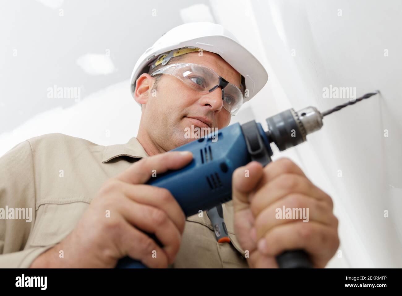 builder drilling the wall with drill perforator Stock Photo - Alamy