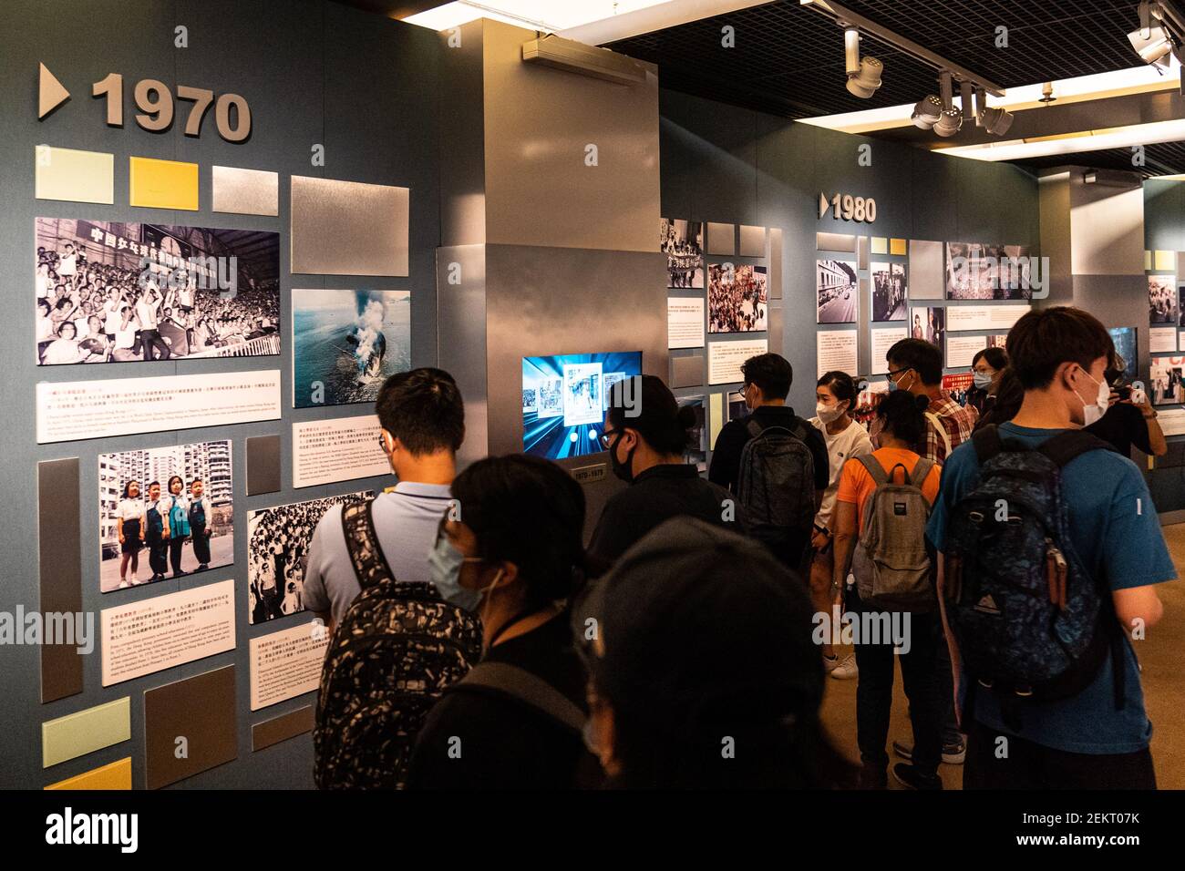Visitors wearing face masks look at the displays at the exhibition. The ...
