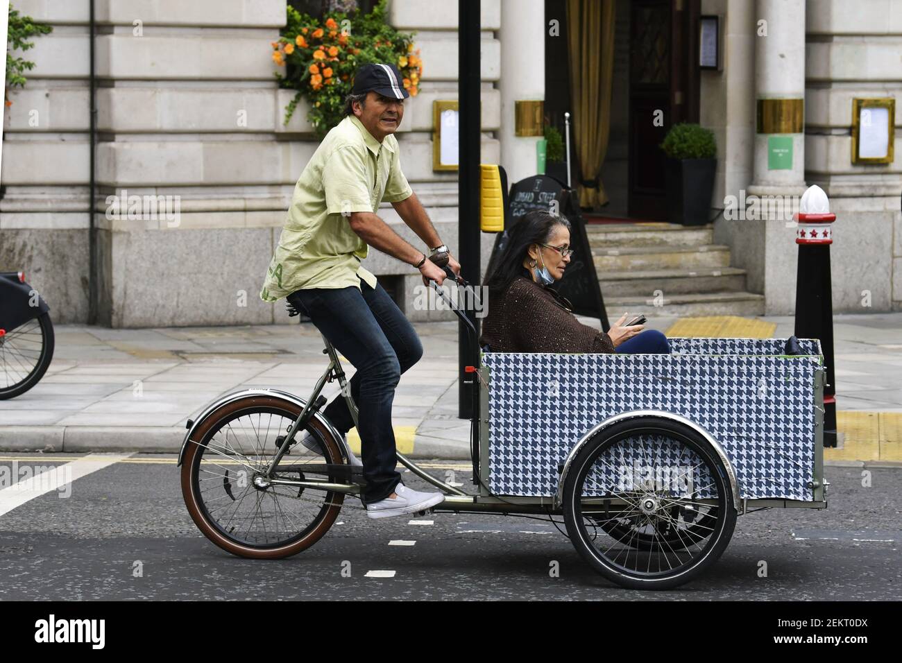 A man riding a tricycle with a woman sitting in a box at the front in ...