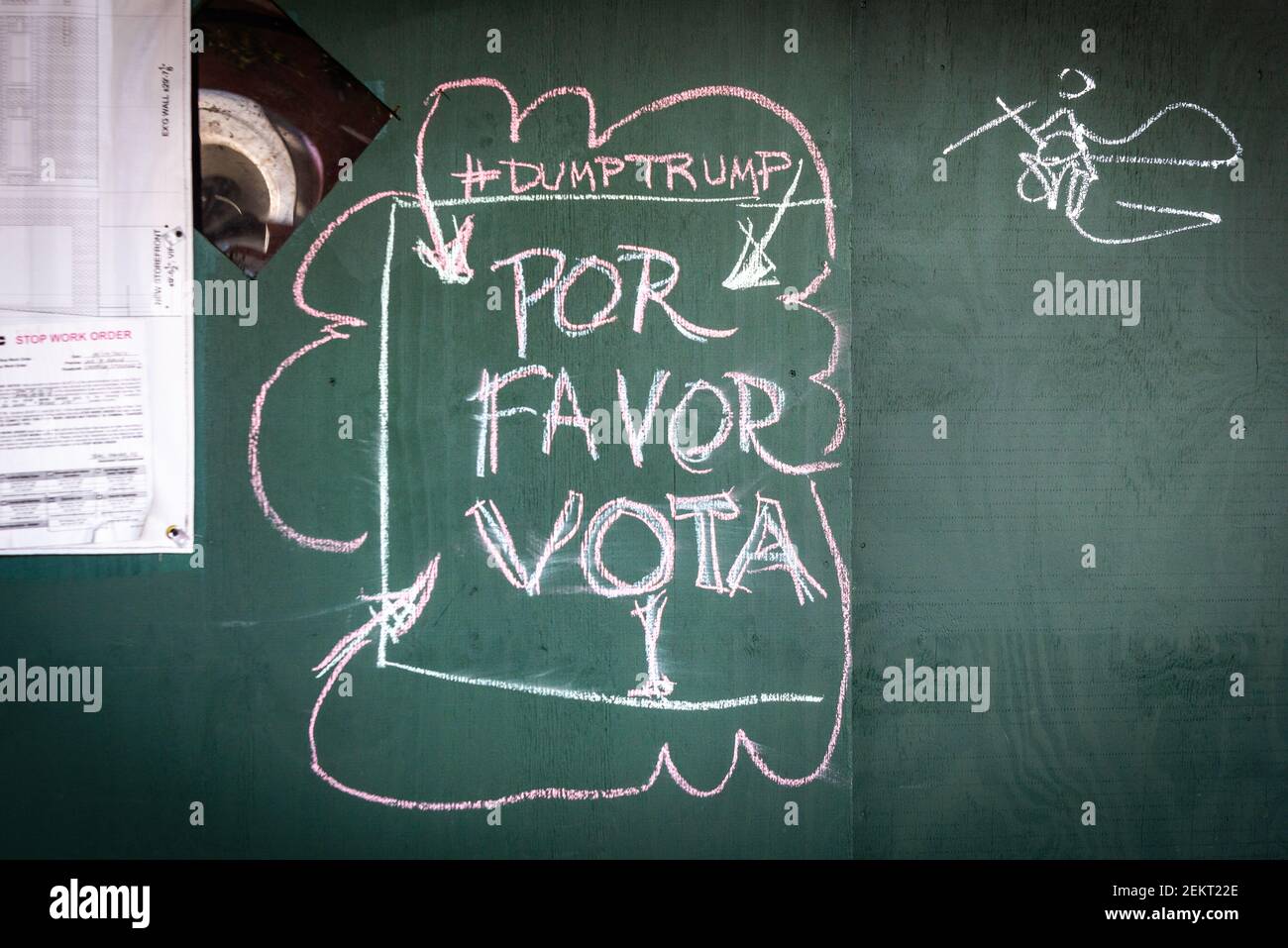 Chalk graffiti imploring people to vote is written on a wooden board in ...