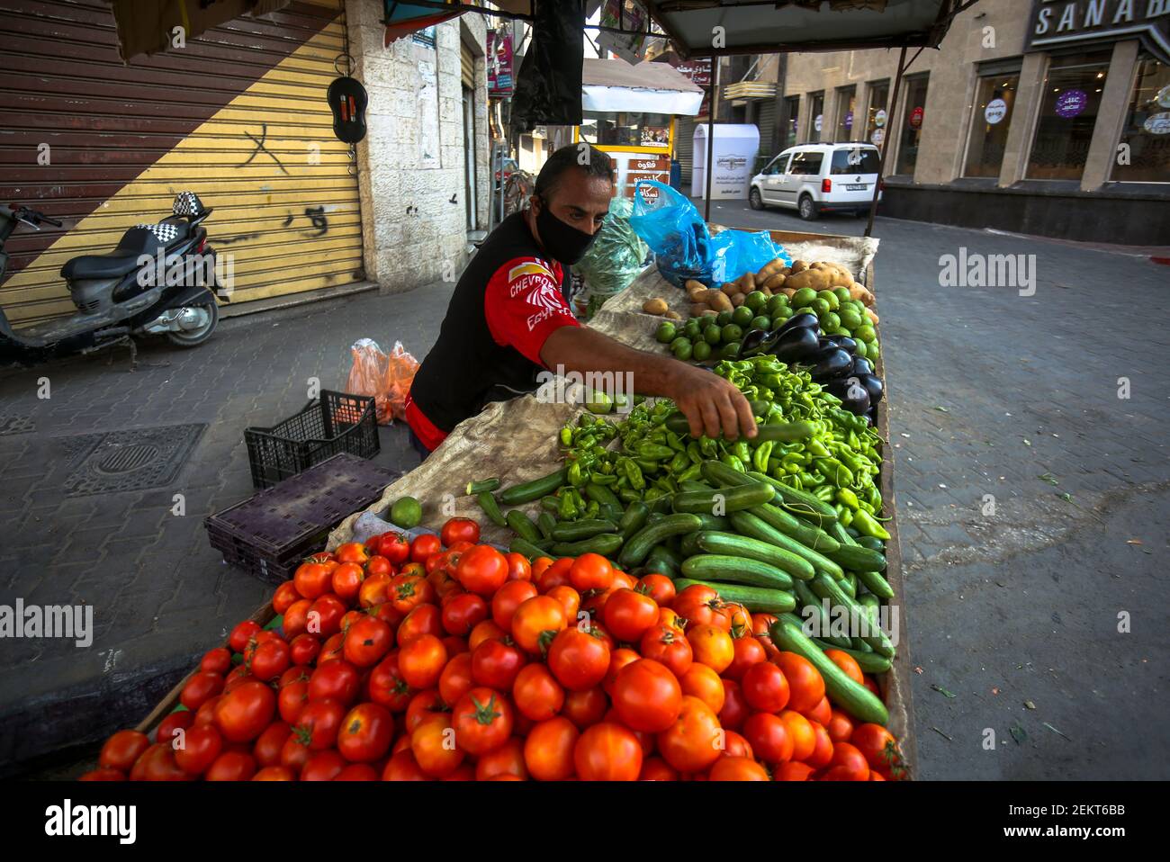 A Palestinian vegetable vendor wearing a face mask in Khan Yunis ...