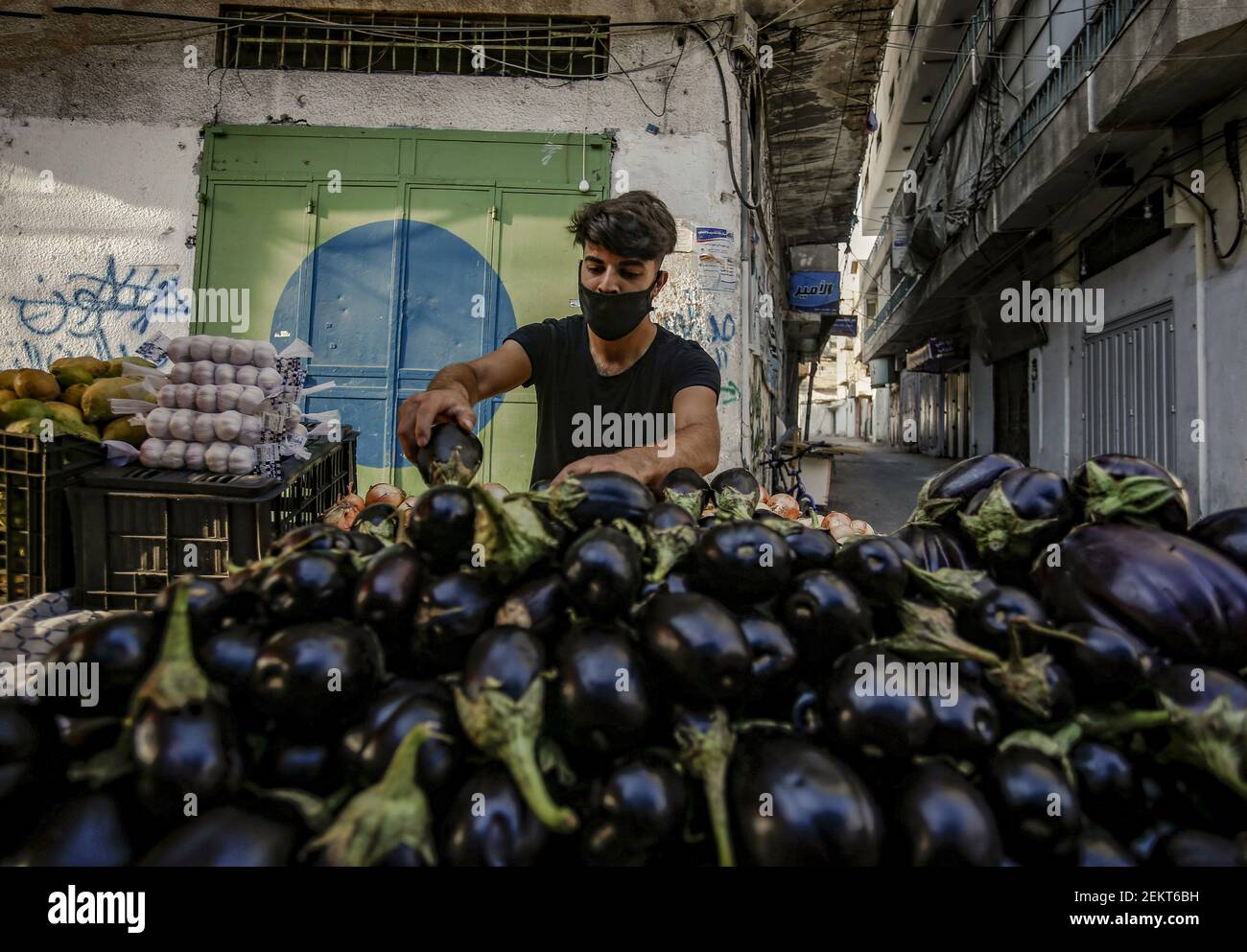 A Palestinian vegetable vendor wearing a face mask in Khan Yunis ...