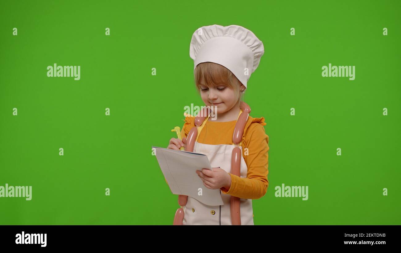 Child girl kid dressed as professional cook chef writing with pen in ...