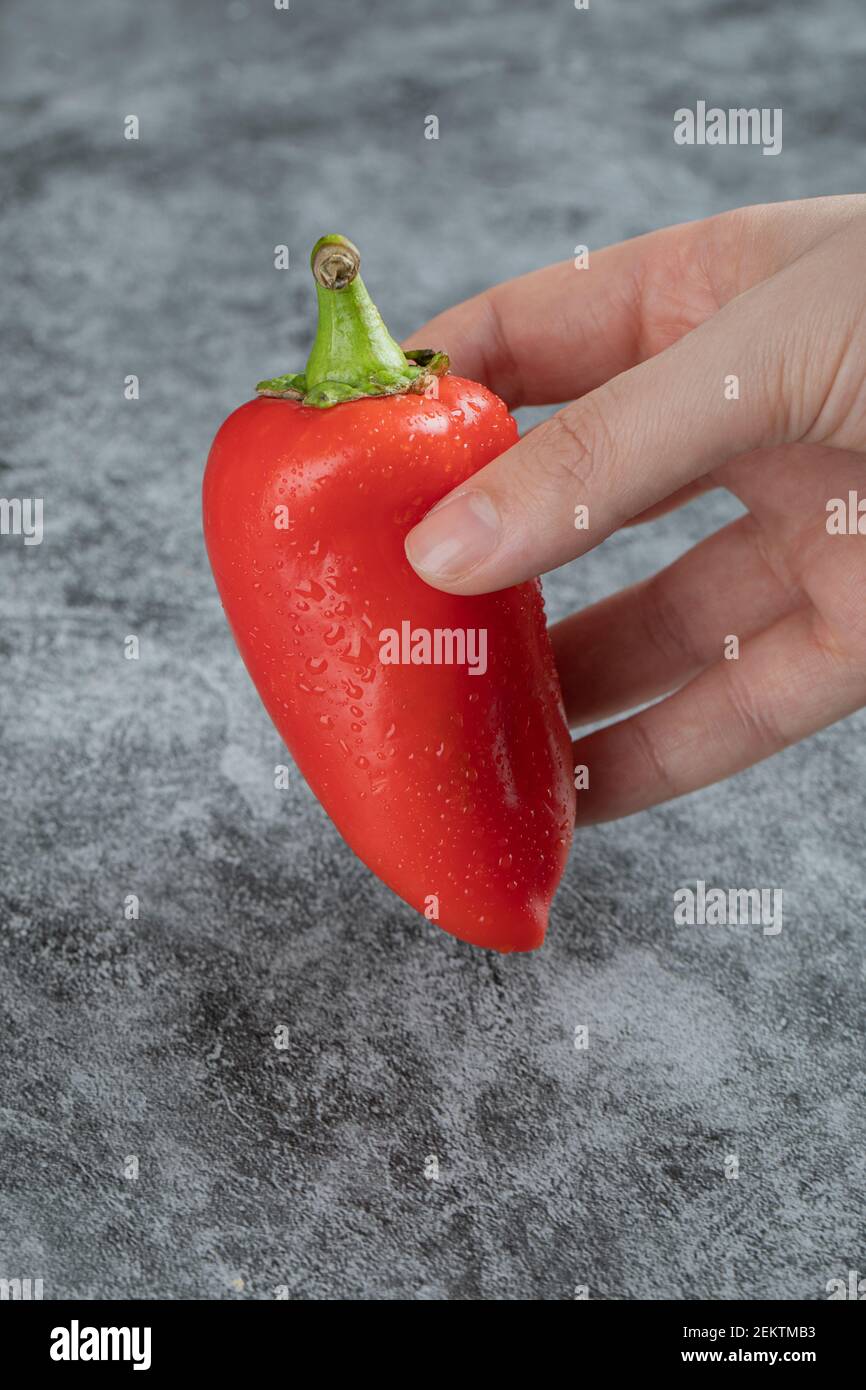 Female hand holding a whole fresh red pepper Stock Photo - Alamy