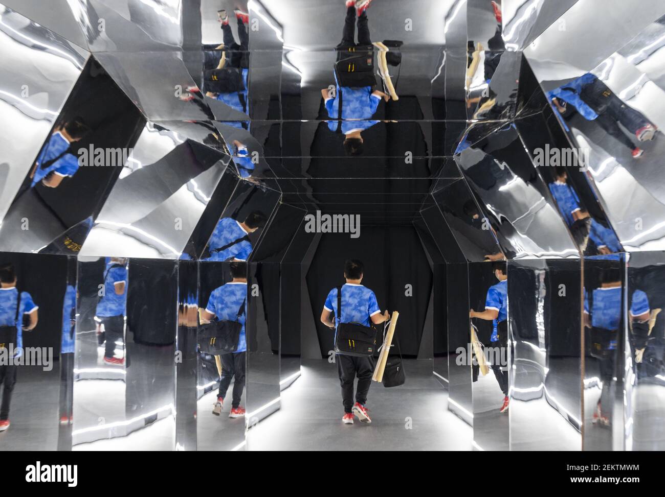 A visitor walks through a hallway covered with mirrors at an exhibition ...