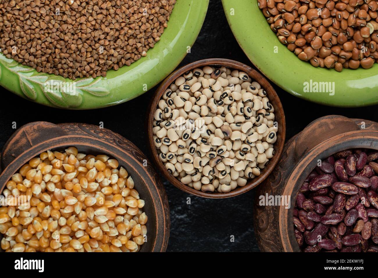 Different kinds of bean seeds, lentil, peas in dishes on a dark ...