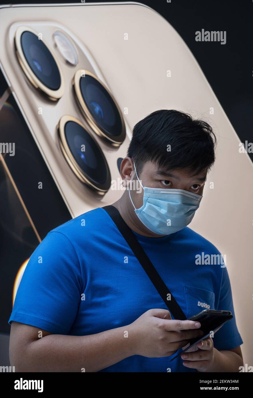 A customer queues in line at an Apple store during the launch day of ...