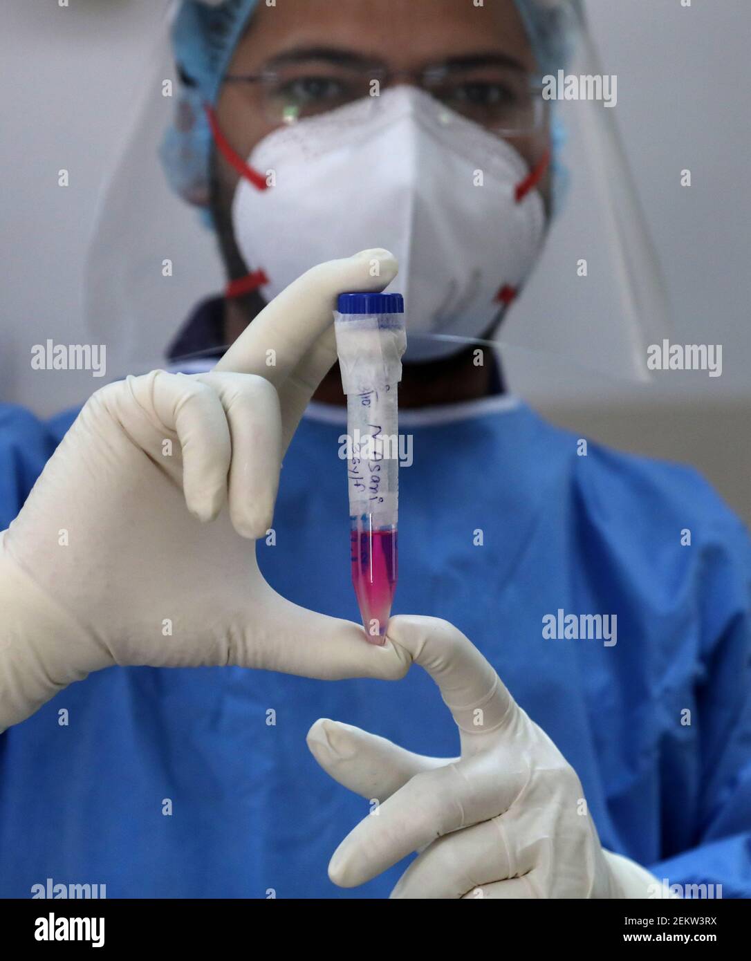 A medic wearing personal protective equipment (PPE) holding a sample ...