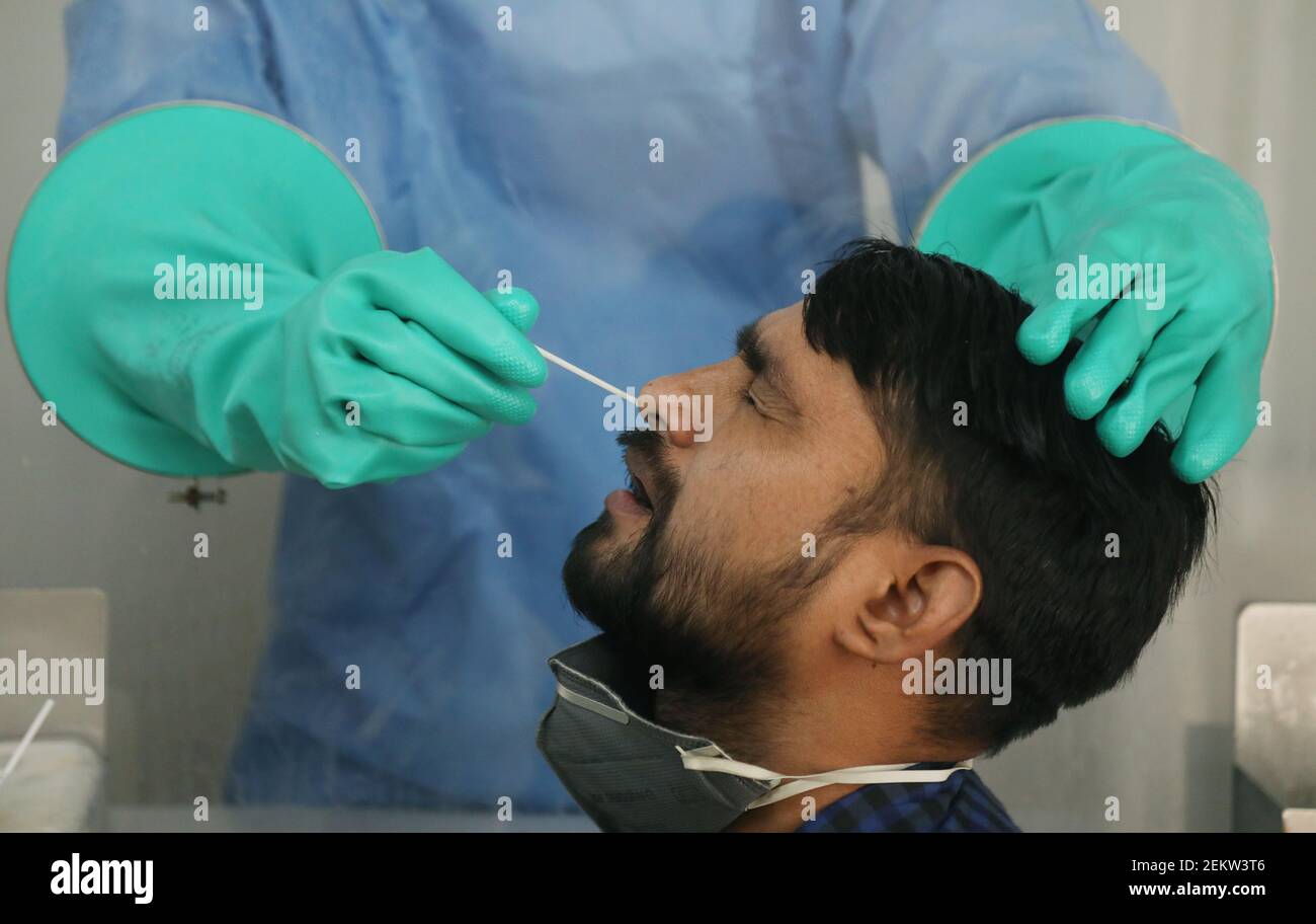 A medic wearing personal protective equipment (PPE) collecting a swab ...