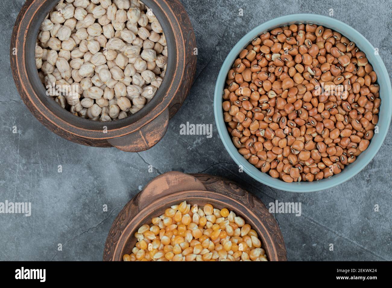Different kinds of bean seeds, lentil, peas in dishes on a dark ...