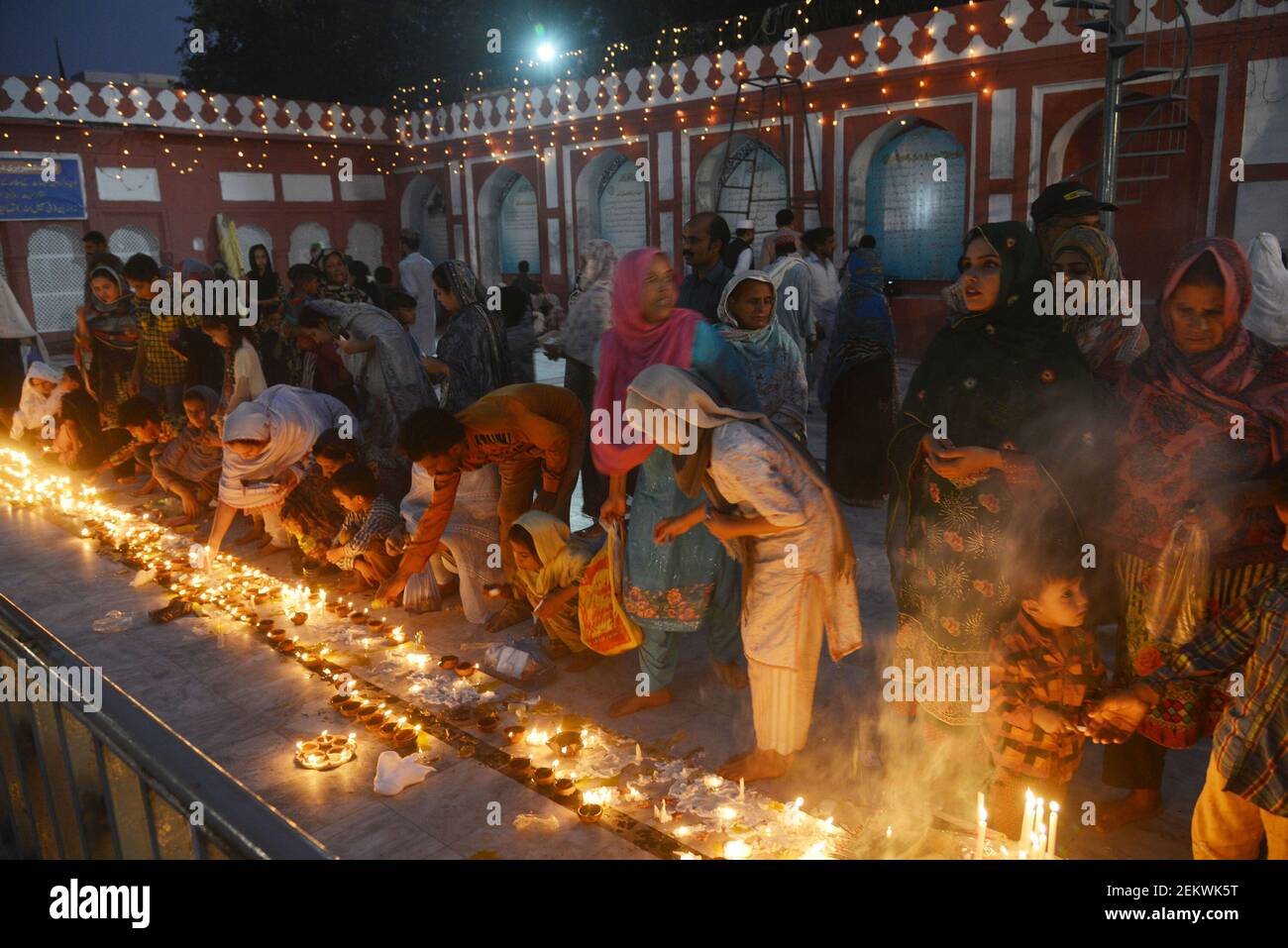 Pakistani Muslim devotees light candles and earthen lamps at the shrine ...