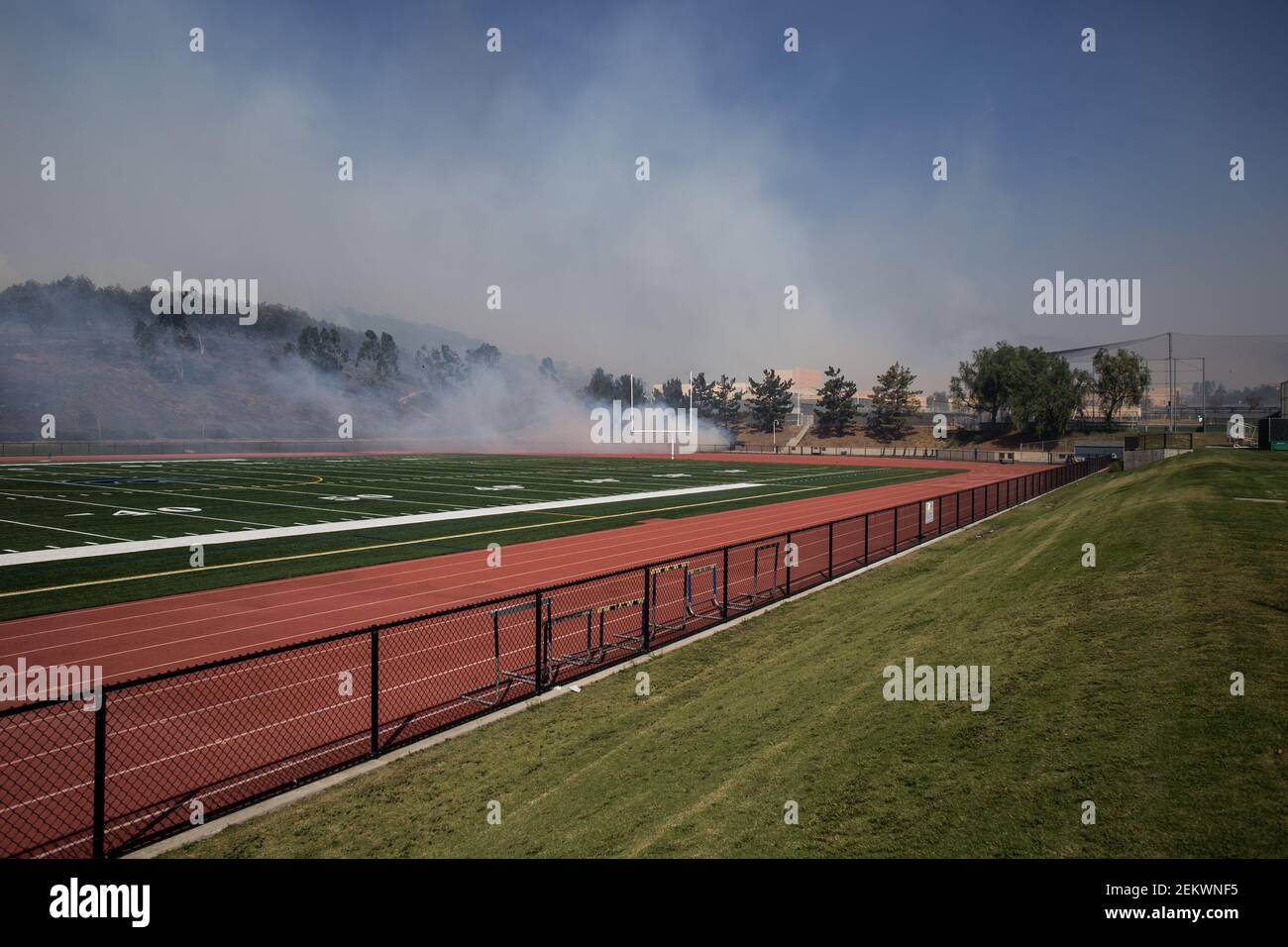 Fire burns in the brush near the football field of Northwood High ...