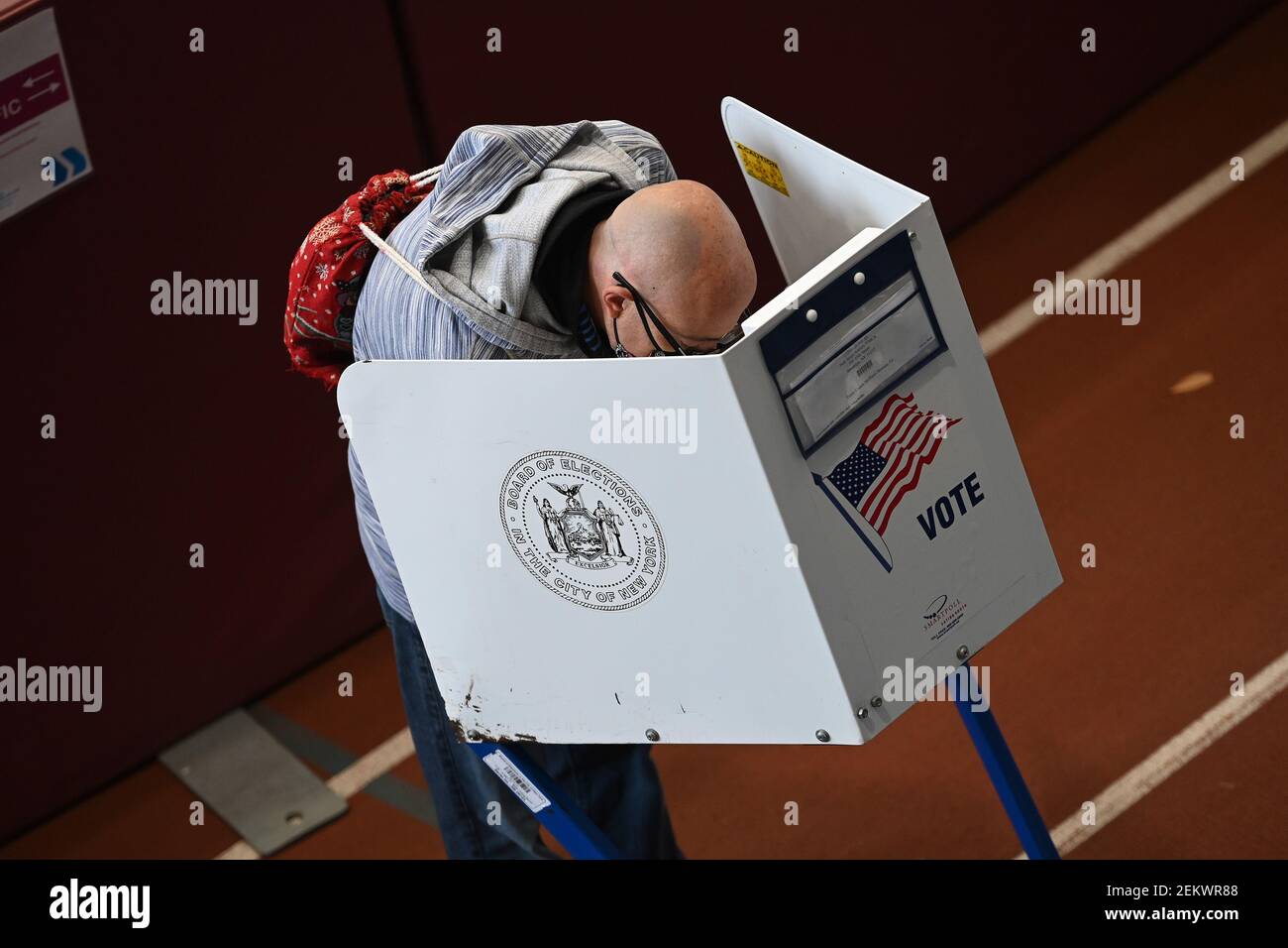 A man stands behind a voter privacy booth as he fills out his ballot to ...
