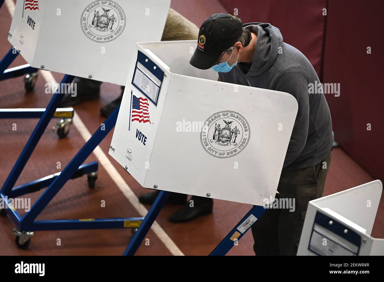 A man stands behind a voter privacy booth as he fills out his ballot to ...