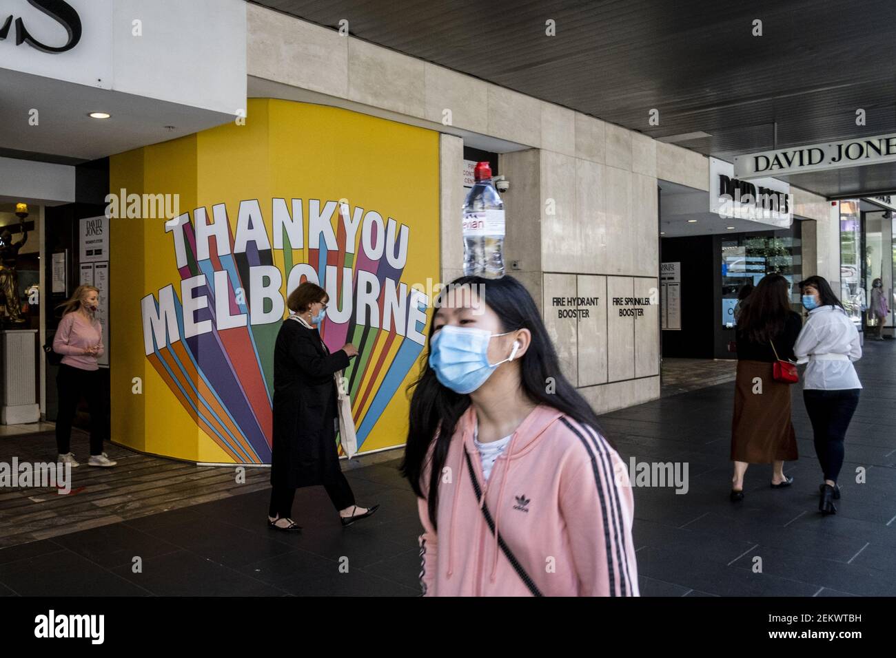 A woman wearing a face mask walks by David Jones windows "Thank You ...