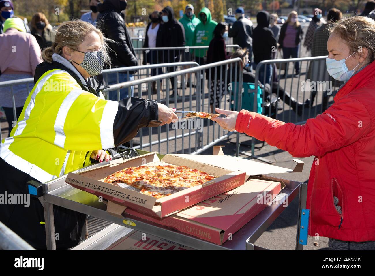 Volunteers offer free pizza to the large crowd of early voters outside ...