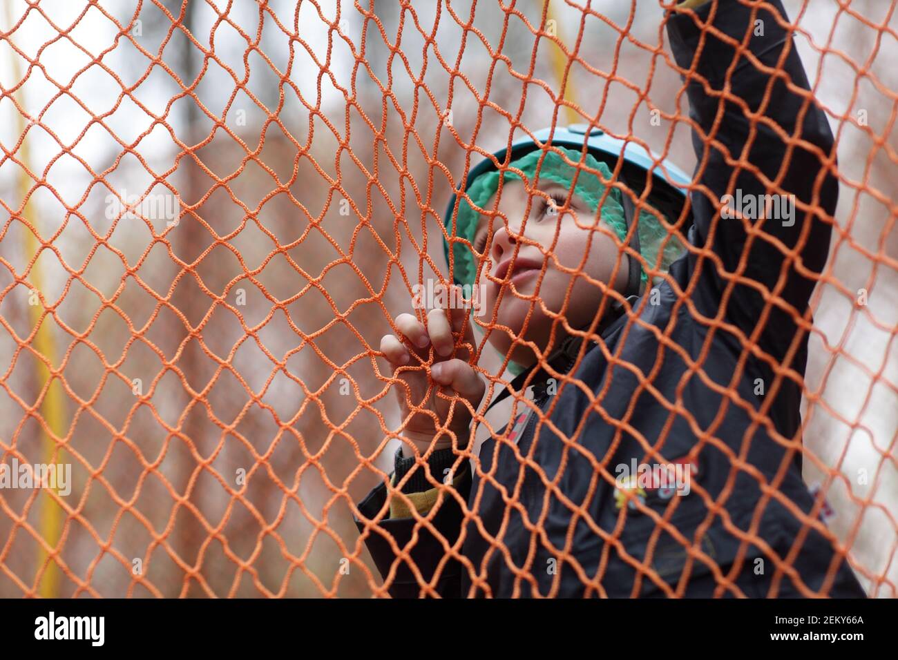 Kid climbing into a net at outdoor playground Stock Photo - Alamy