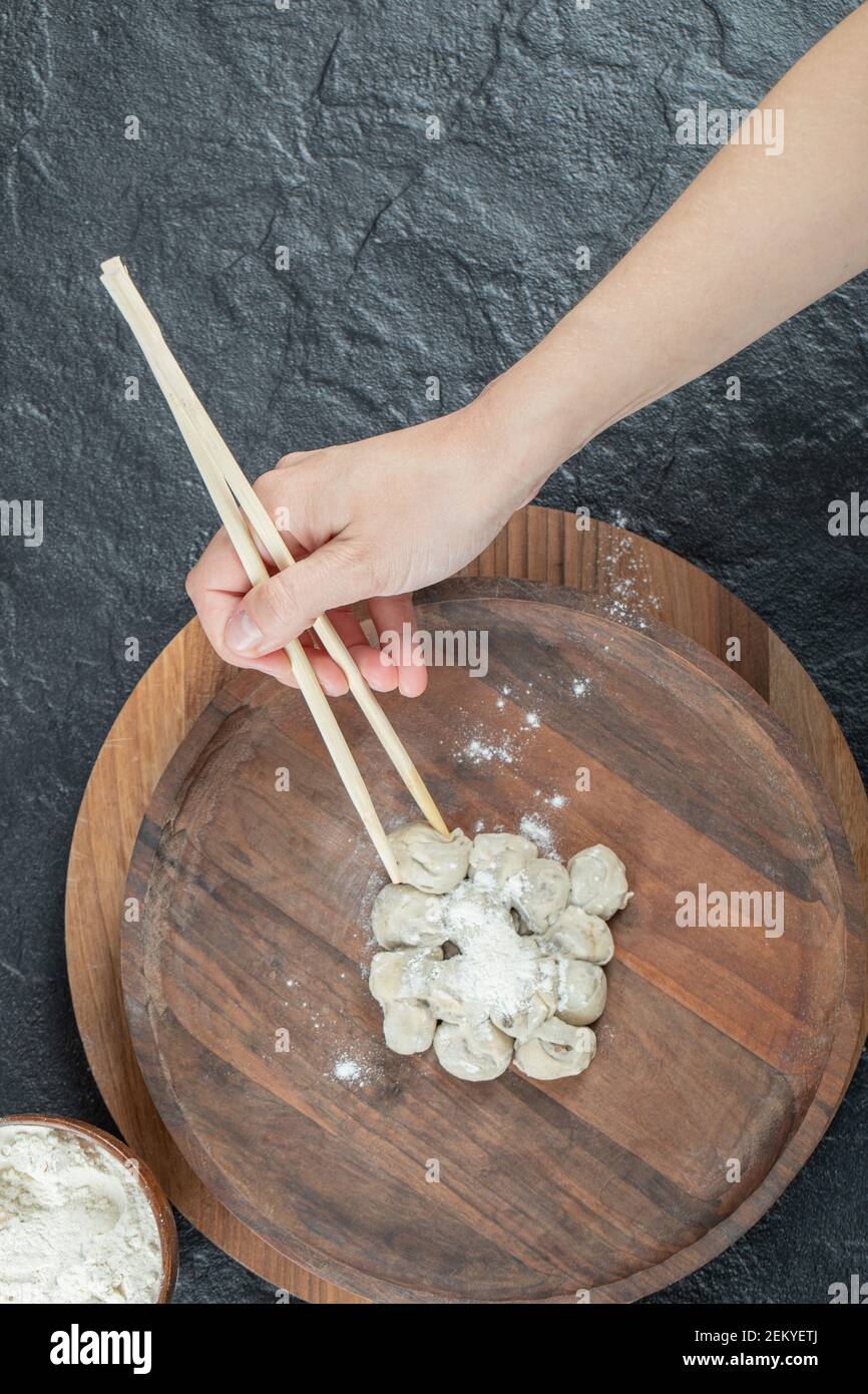 Hand holding a chopstick with a dumpling Stock Photo - Alamy