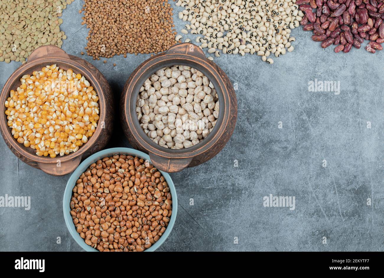 Different kinds of bean seeds, lentil, peas in dishes on a dark ...