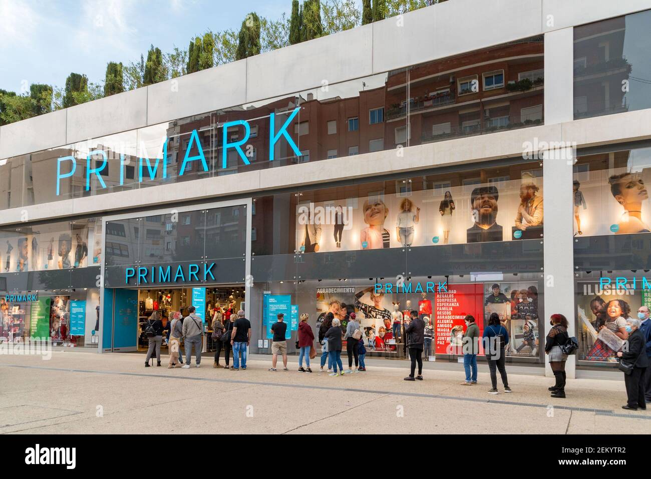 People wearing face masks stand in a queue outside the Primark clothing ...
