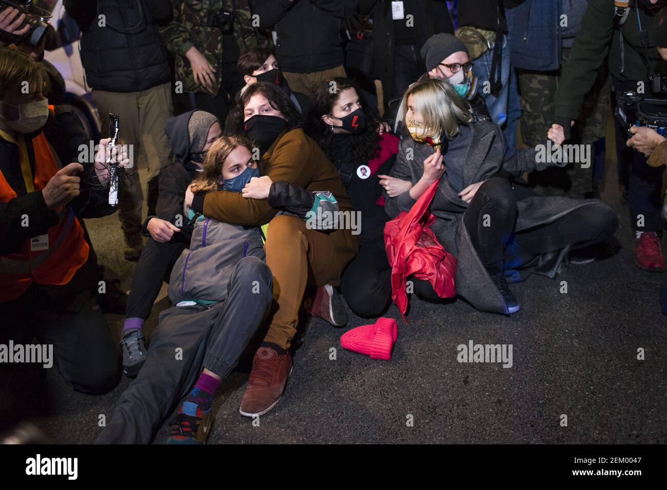 Protesters wearing face masks hold each other on the street while ...