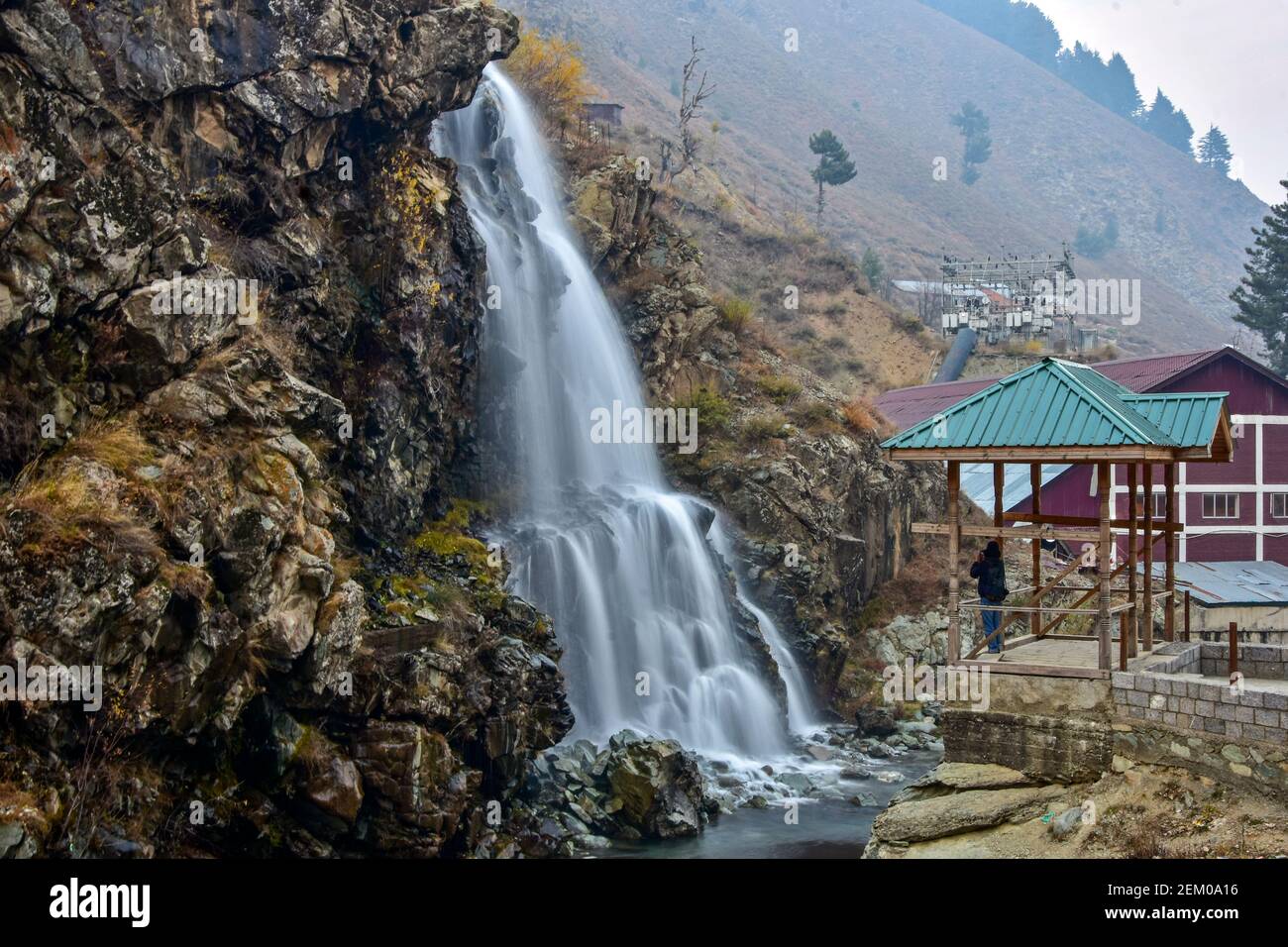 A visitor takes pictures of the waterfalls on an autumn day in Drang ...