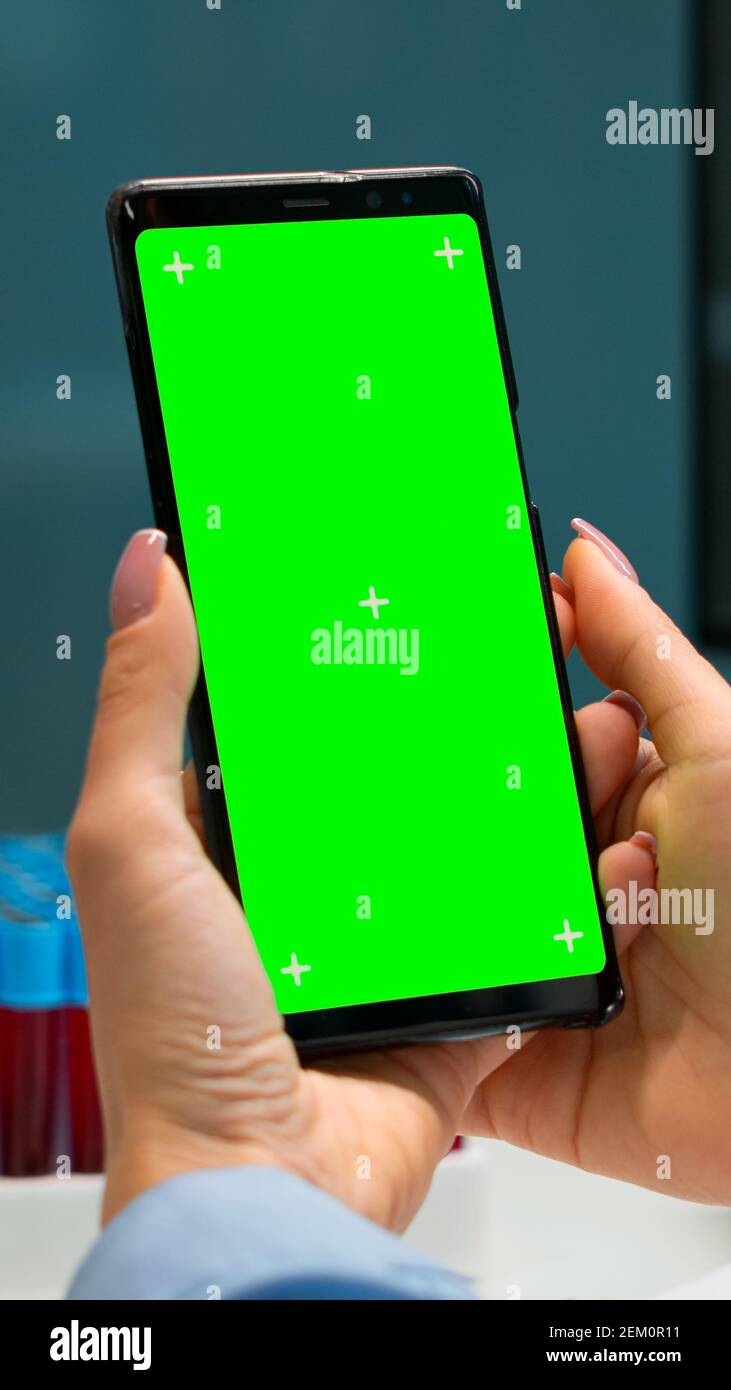 Close up of doctor's hand holding phone with green screen sitting at ...