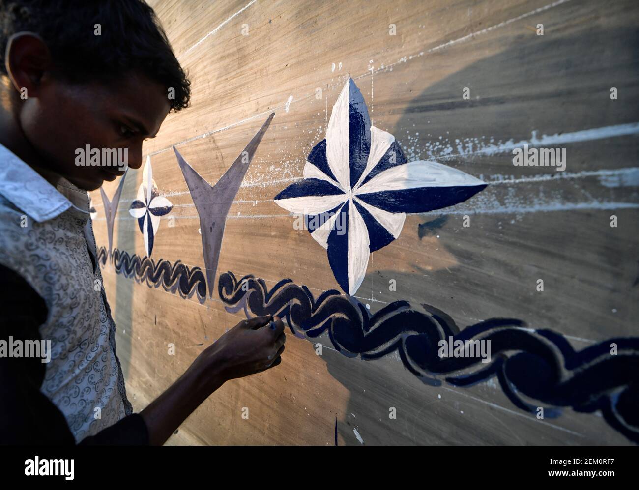 An artist seen decorating a wall of a house with colourful designs ...