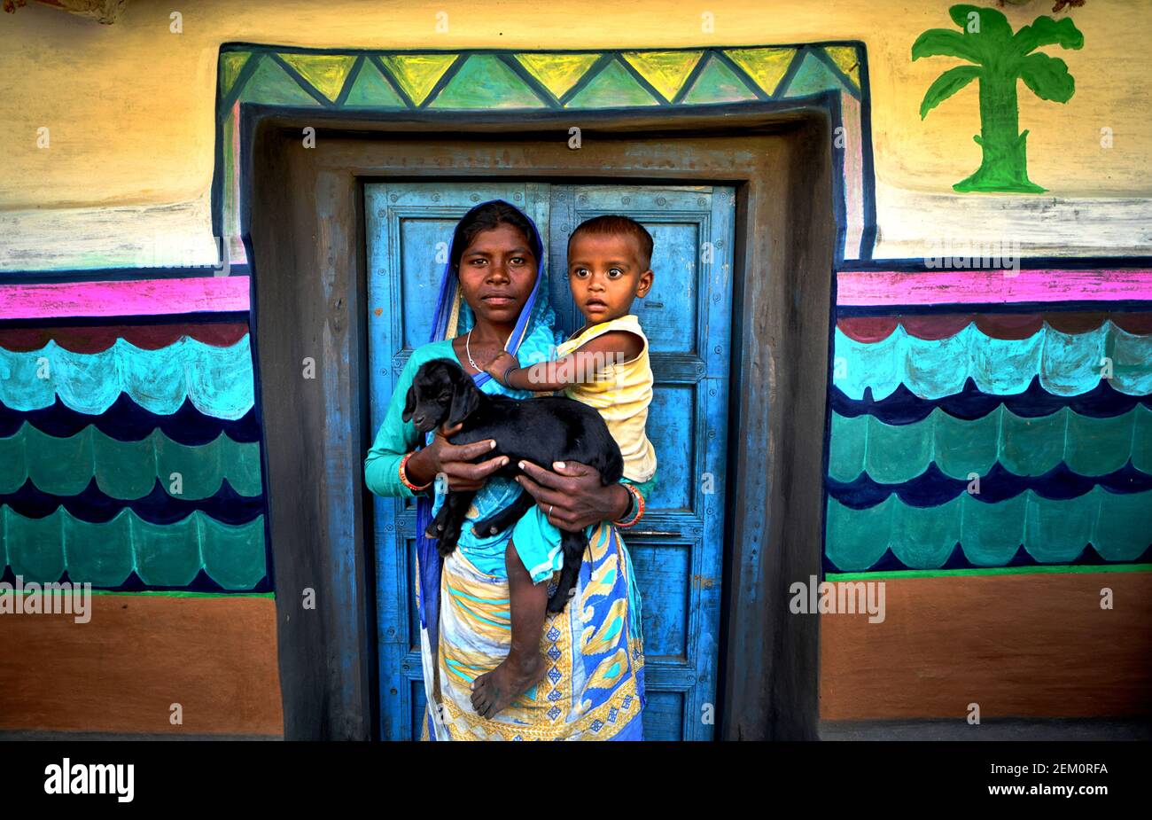A mother and son pose for a photo with their goat in front of their ...