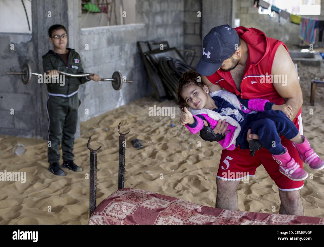 A Palestinian bodybuilder training with his kid at home amid the ...