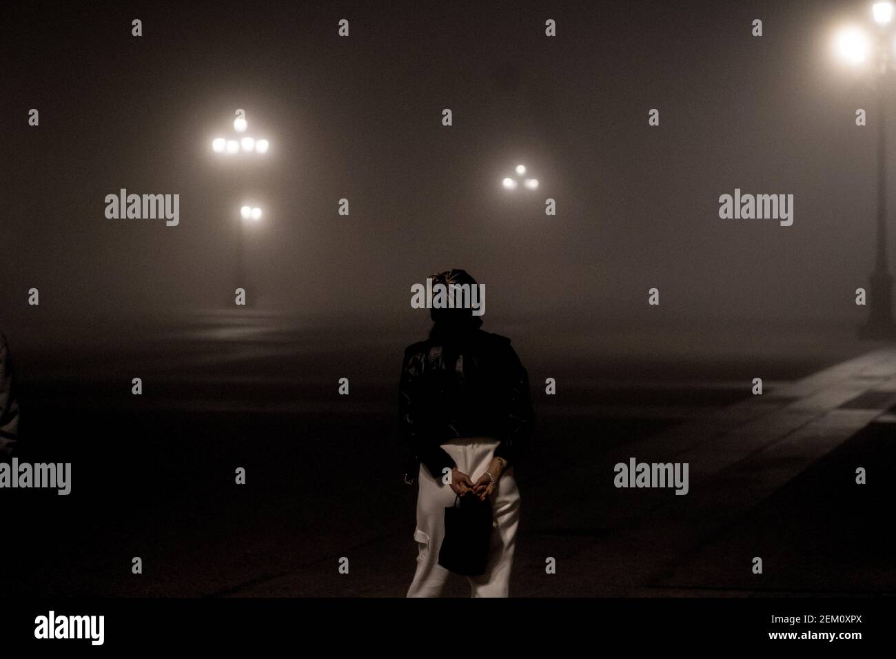 A woman observes the dense fog at the royal palace square in Madrid ...