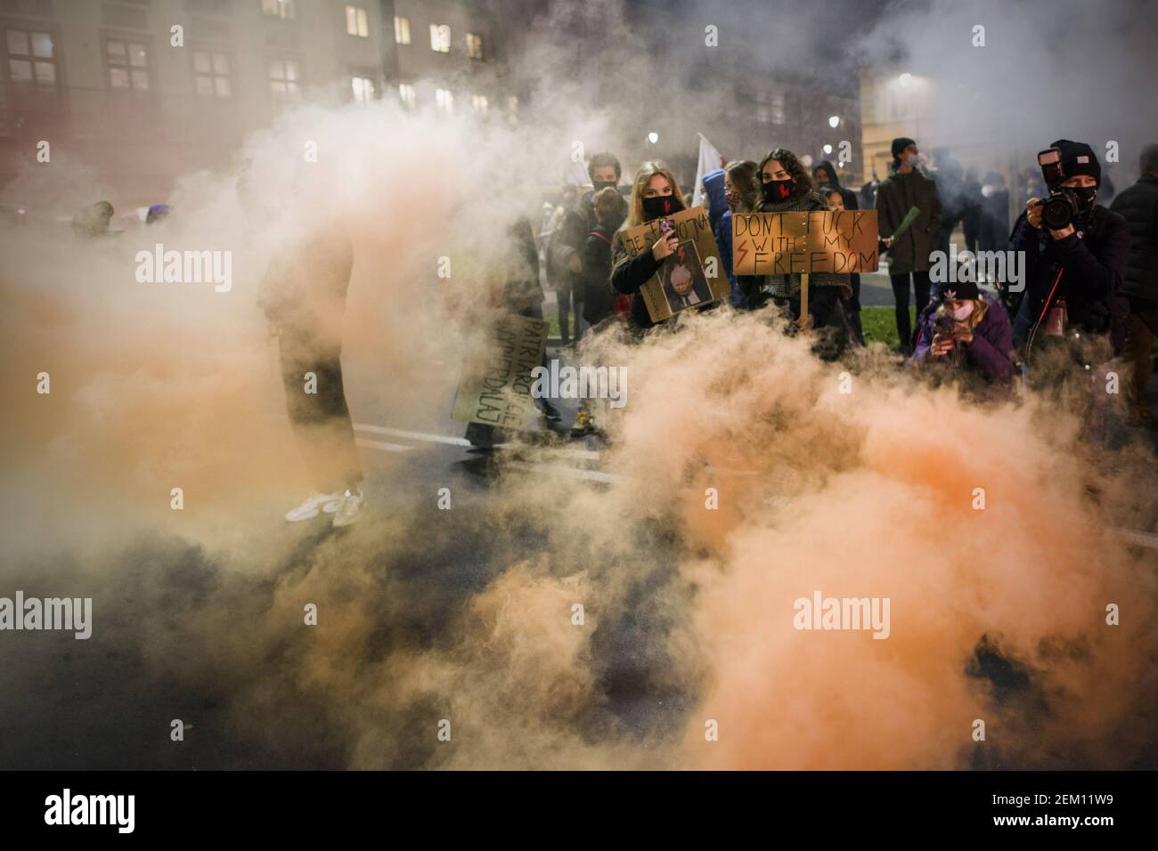 Protesters hold placards and chant slogans amidst teargas smoke during ...