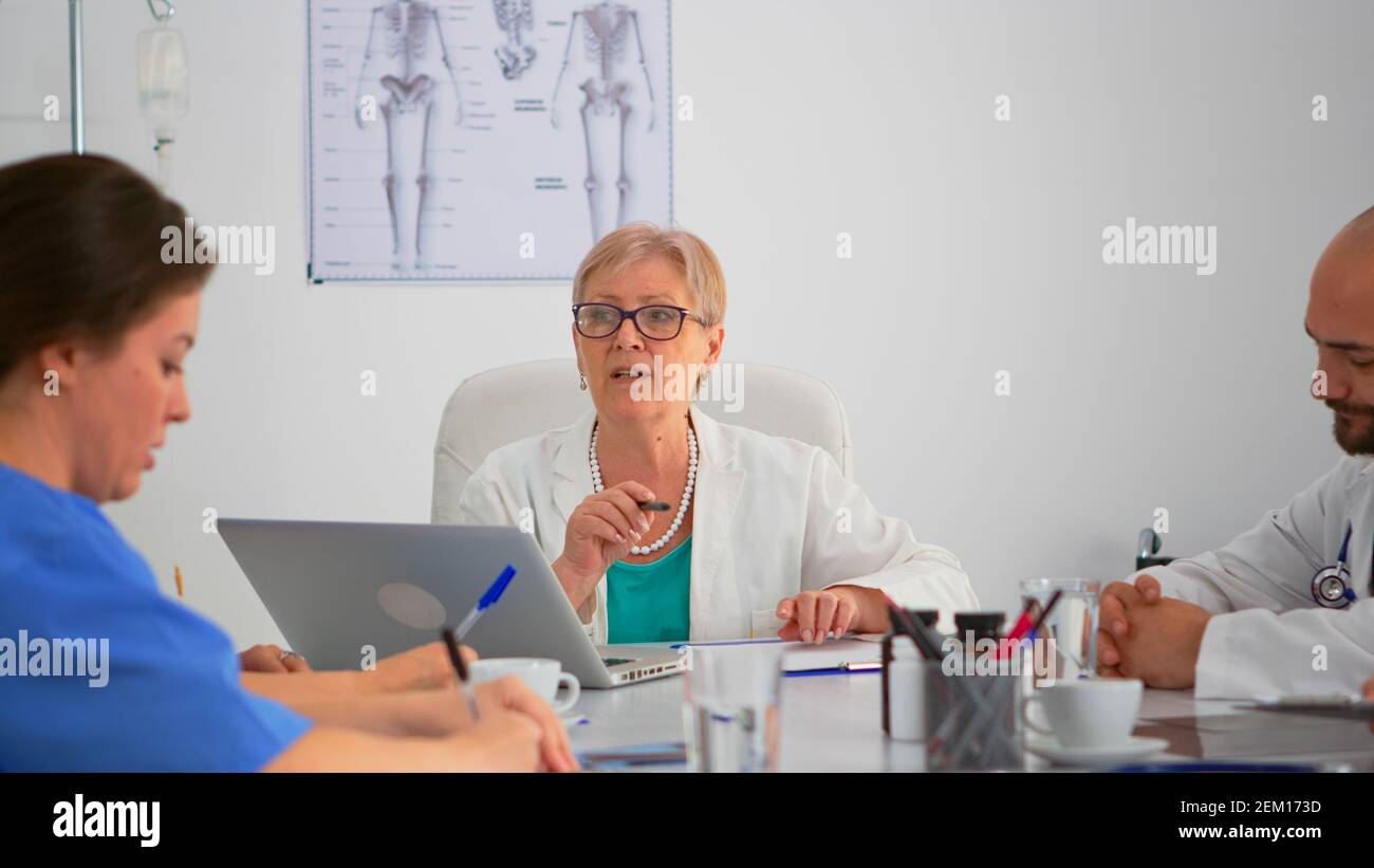 Senior surgeon explaining treatment to coworkers presenting plan during ...
