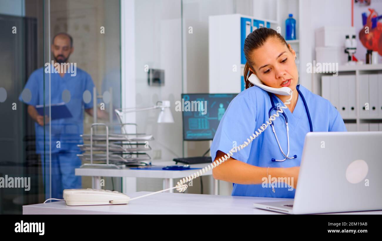 Medical assistant speaking at phone with patient analysing ...